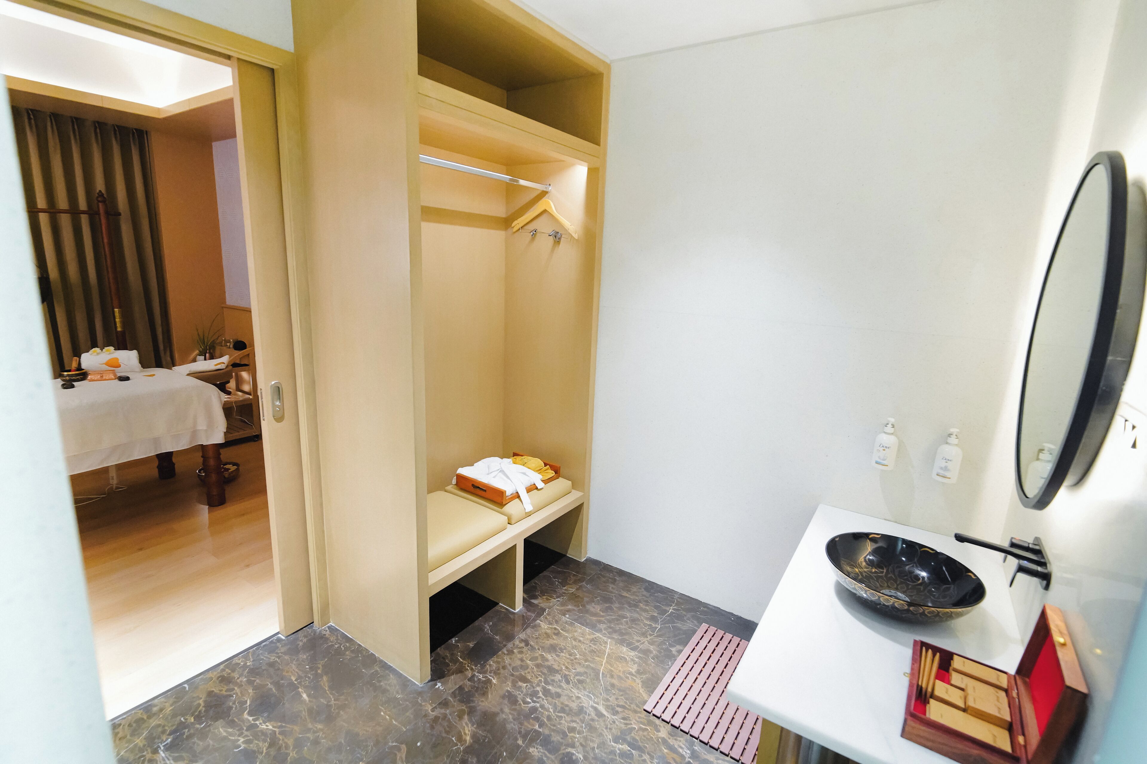 Quarto de hotel com uma cama beliche, uma mesa de cabeceira com uma tigela, um espelho e uma pequena caixa de madeira.