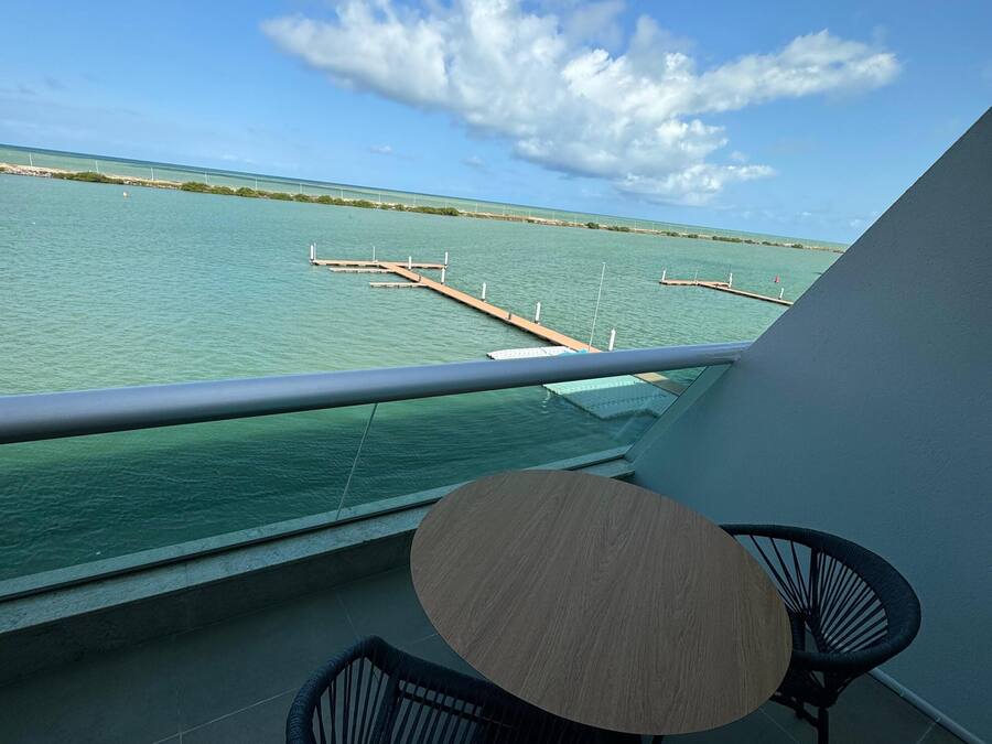Uma varanda com vista para o mar, uma mesa redonda e duas cadeiras.