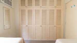 Quarto com duas camas, um guarda-roupa grande e um espelho na parede.