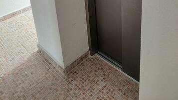 Canto de um quarto com uma porta de elevador metálica e uma parede texturizada.