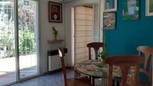 Uma sala de jantar com mesa e cadeiras, porta de vidro deslizante e parede azul com obras de arte emolduradas.