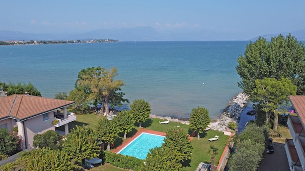 Zona residencial com piscina, árvores e vista para o mar.
