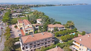 Um bairro residencial com casas próximas a um lago, apresentando uma estrada, áreas verdes e uma piscina.