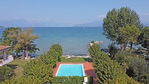 Piscina com vista para o mar, cercada por árvores e um edifício.
