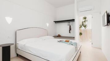 Quarto moderno com cama, mesa de cabeceira e televisão na parede.