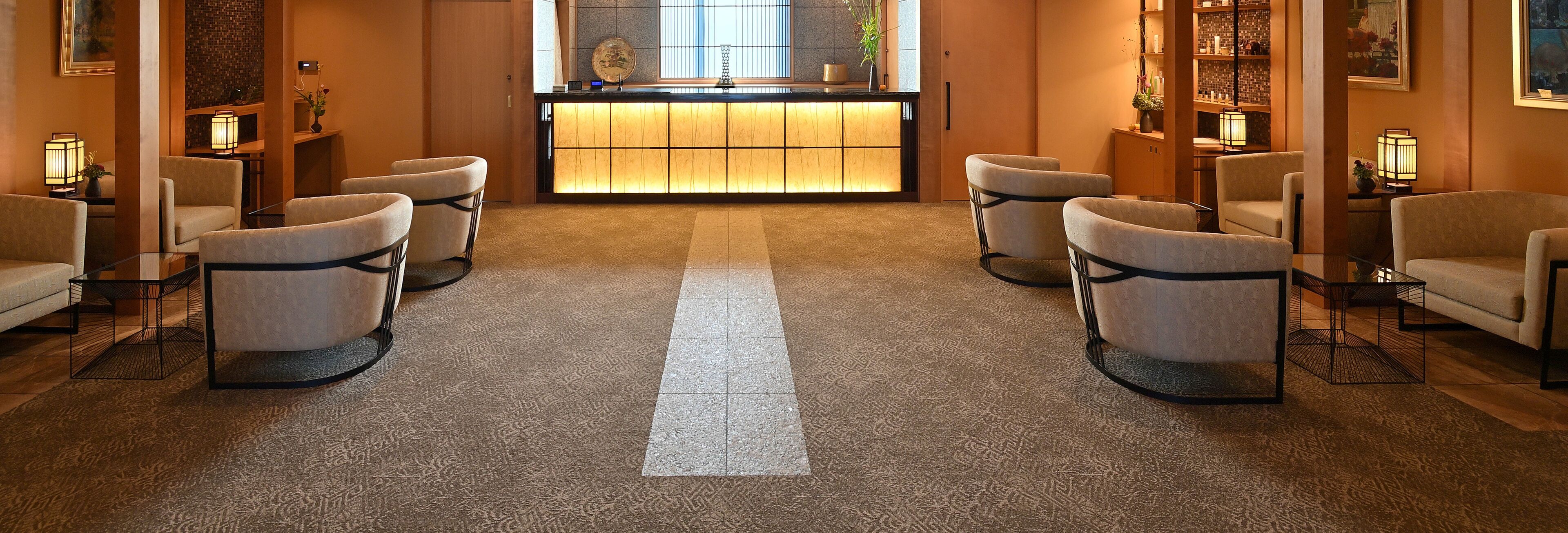 Um saguão de hotel com balcão de recepção, área de estar e elementos decorativos.