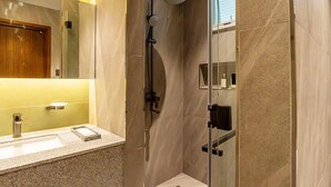 Uma casa de banho moderna com cabine de duche em vidro, toucador com lavatório e espelho.