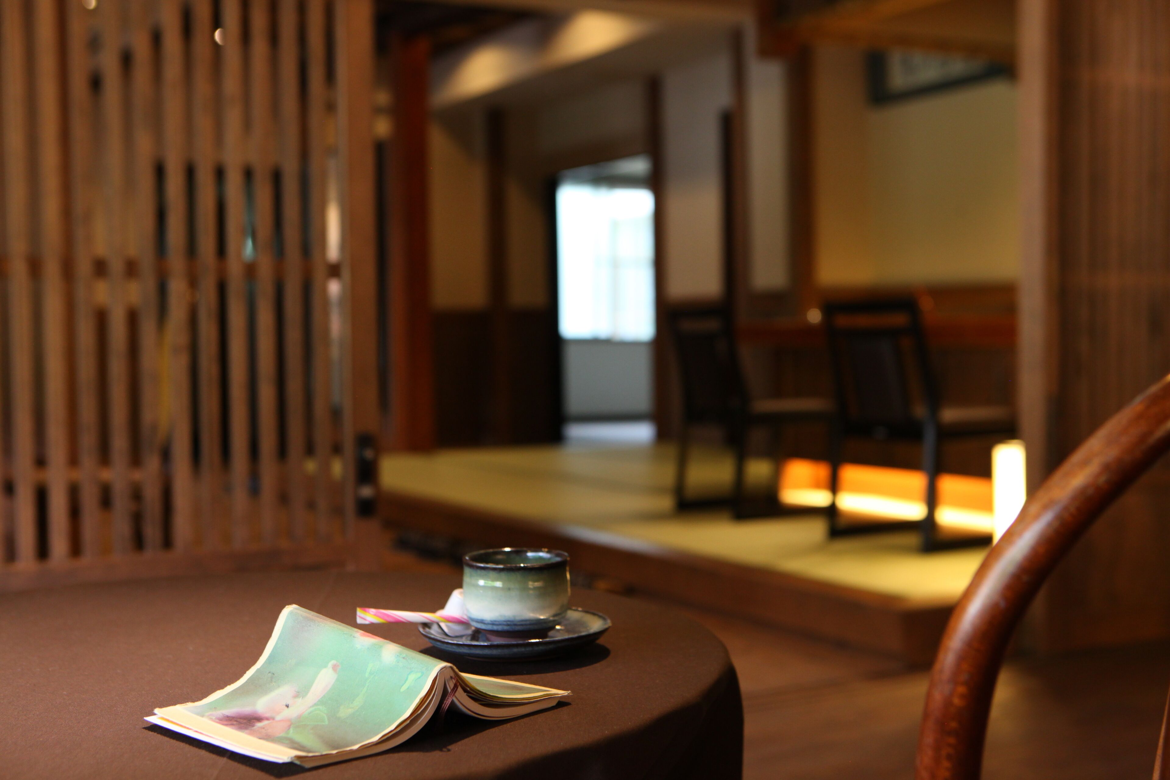 Um quarto japonês tradicional com tatames, uma mesa baixa e um conjunto de chá, e portas deslizantes.