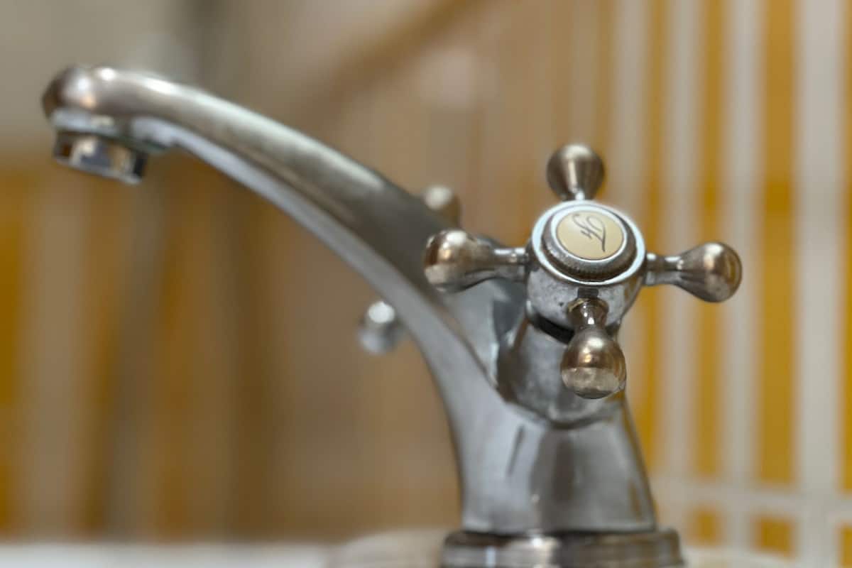 Uma pia de banheiro com uma torneira cromada e um dispensador de sabonete.