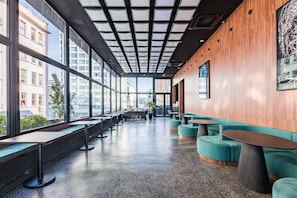 Interior moderno com um amplo banco, detalhes em madeira e grandes janelas com vista para a cidade.