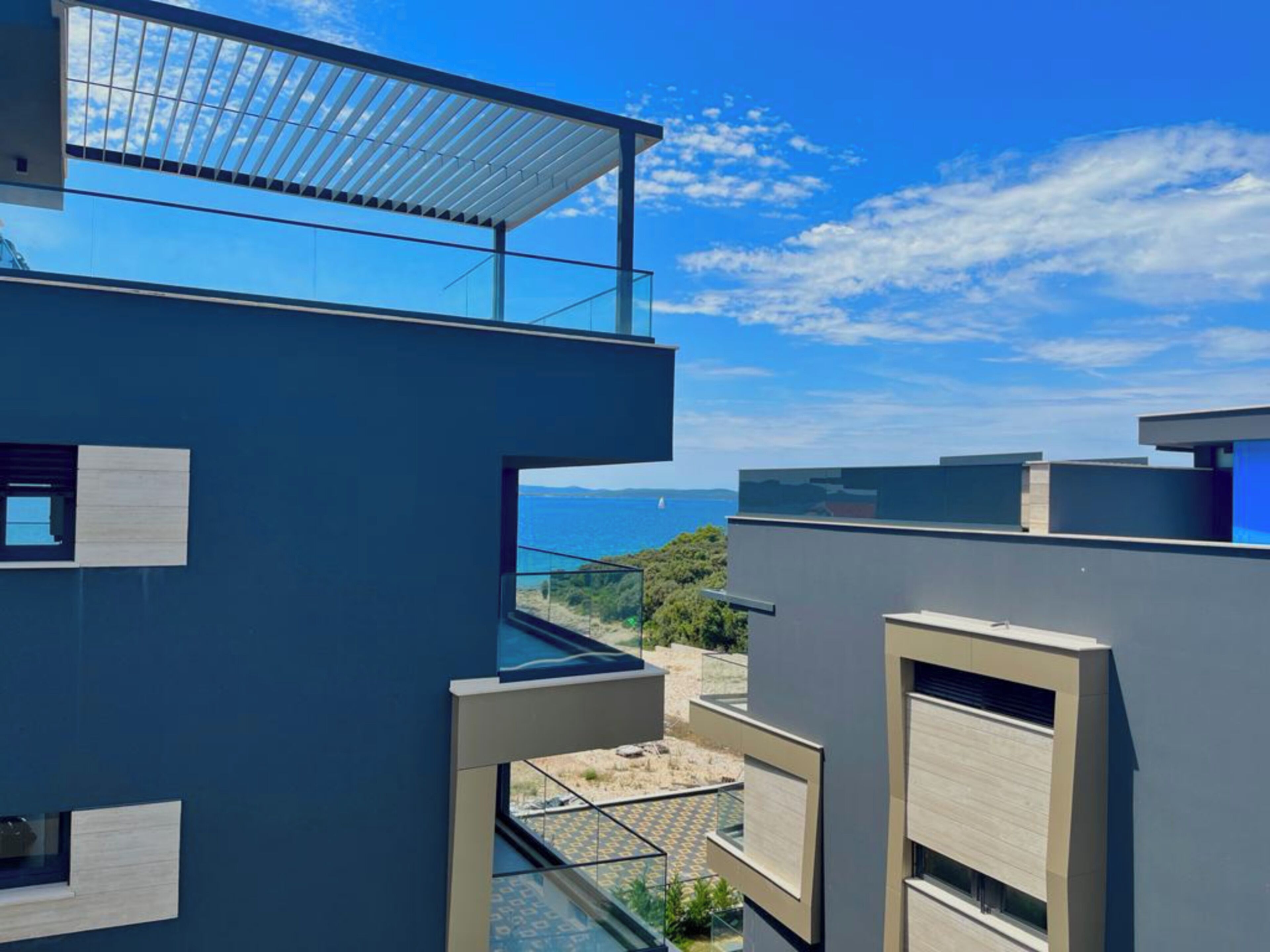 Um edifício moderno com terraço no telhado e vista para a água.