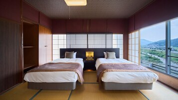Quarto de hotel com duas camas, uma janela ampla com vista e cabeceira de estilo tradicional japonês.