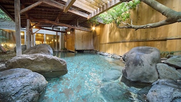 Uma onsen japonesa tradicional, com interior em madeira, nascente quente de pedra e vista para a natureza ao redor.