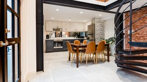 Uma cozinha moderna com armários brancos, uma mesa de jantar com cadeiras e uma escada em espiral.
