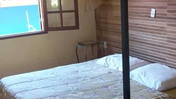 Quarto com cama, ventilador de teto, janela com vista e mesa de cabeceira.