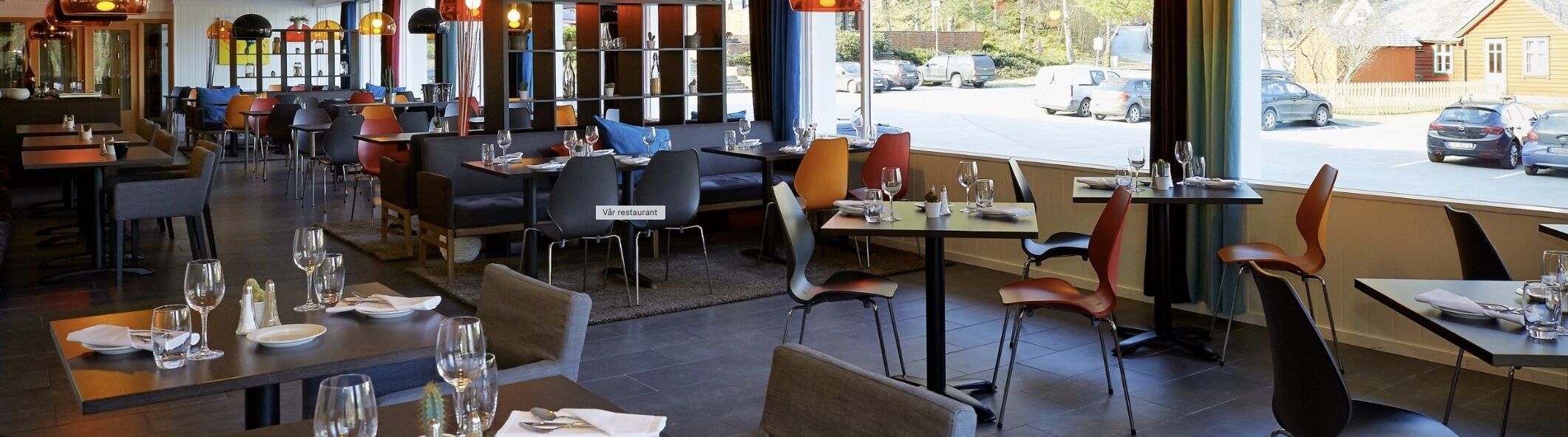 Um restaurante com mesas, cadeiras e um balcão, com vista para a rua.