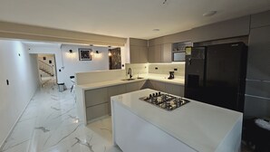 Uma cozinha moderna com ilha central, eletrodomésticos de aço inoxidável e piso de mármore.