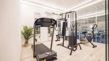 Academia moderna com equipamentos de cardio, máquinas de peso e esteira.