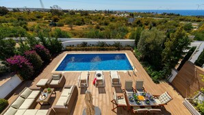 Piscina no terraço com espreguiçadeiras e uma mesa de jantar.