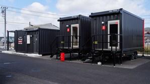 Dois contentores de transporte pretos com escadas externas, um hidrante e uma caixa de correio vermelha.