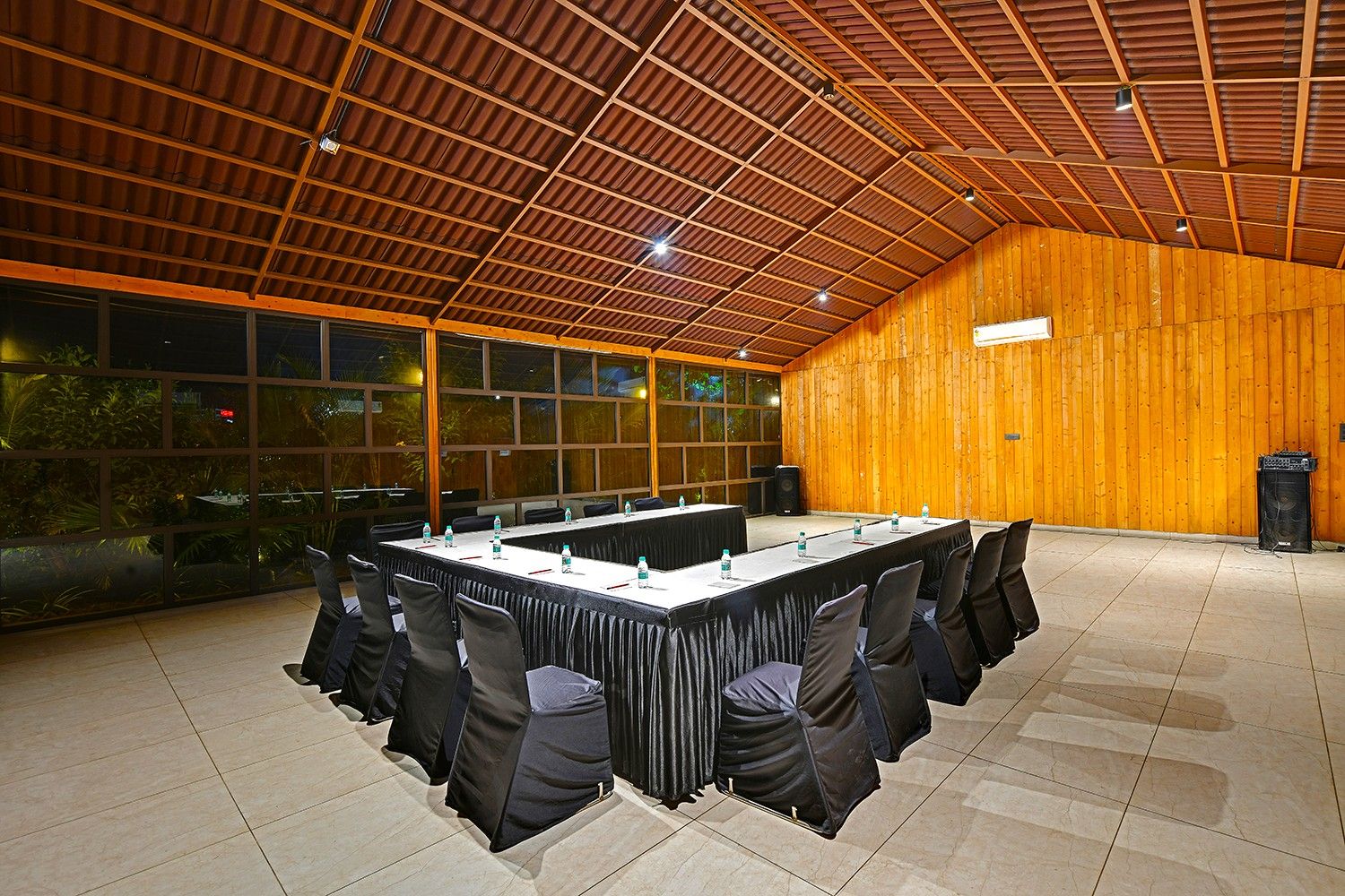 Uma sala de conferências com uma mesa comprida, cadeiras e uma parede de madeira.