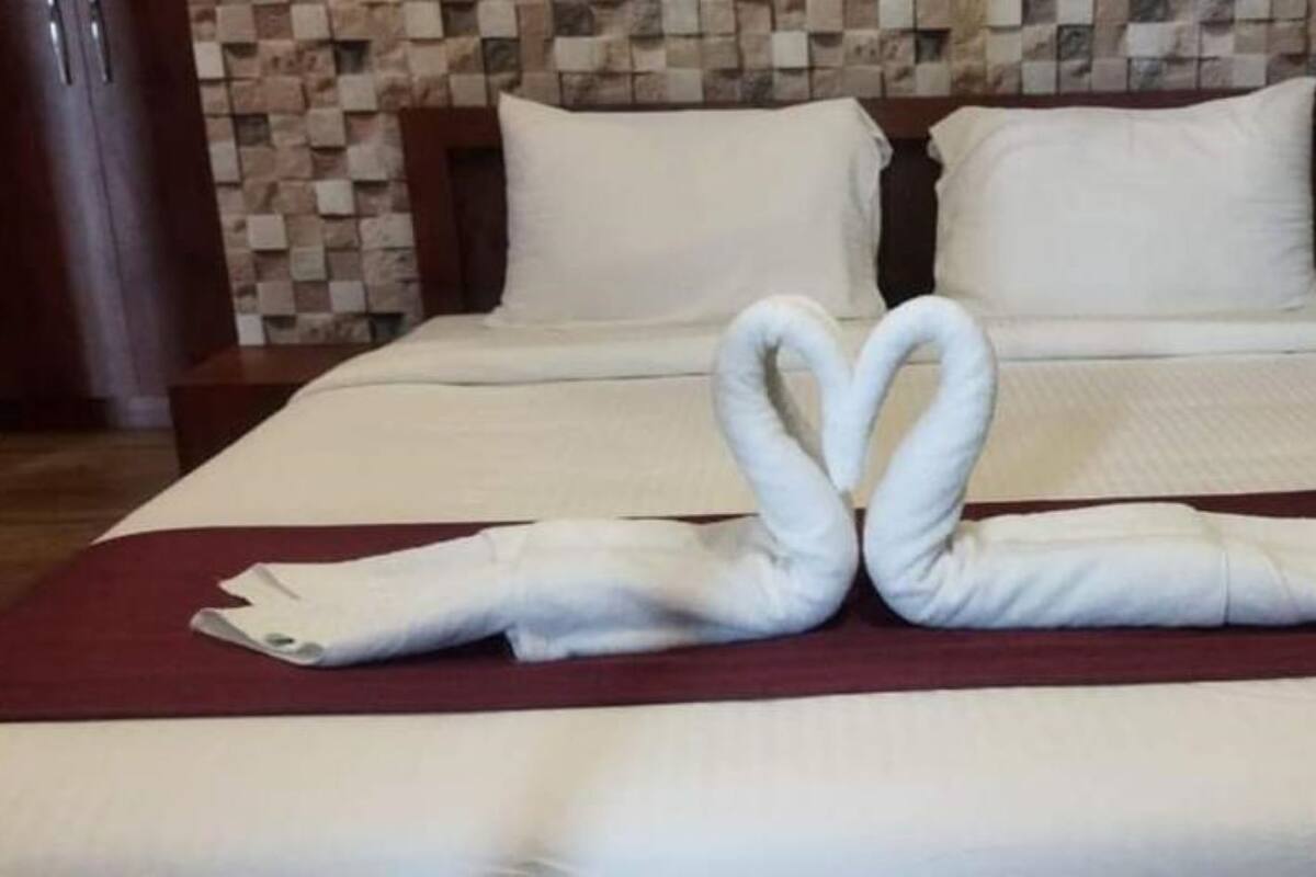 Quarto de hotel com uma cama bem arrumada, parede xadrez e porta de madeira.