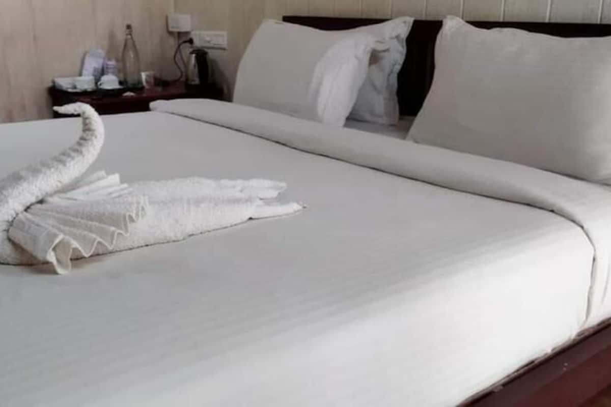 Cama bem arrumada com uma toalha dobrada em formato de cisne.