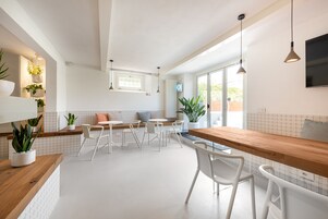 Uma cozinha moderna com armários brancos, bancada de madeira e um espaço de estar com cadeiras brancas e uma mesa redonda.