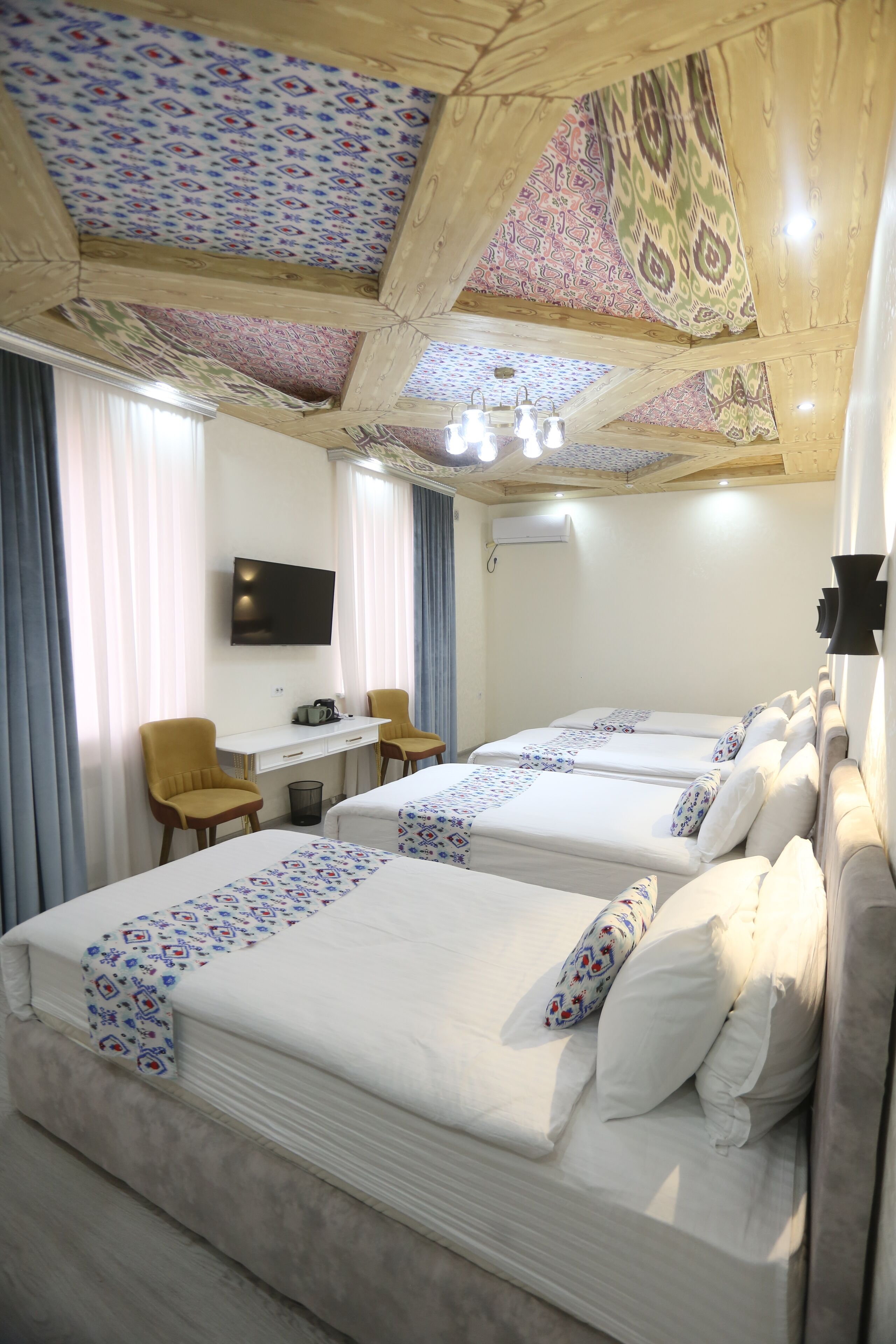 Quarto de hotel com duas camas, uma escrivaninha, uma cadeira e uma televisão.