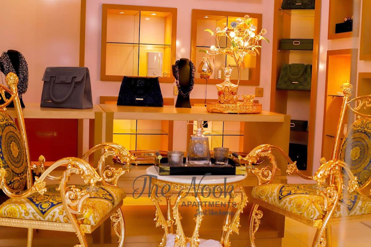 Um interior luxuoso com móveis dourados ornamentados, um candelabro e uma coleção de bolsas.