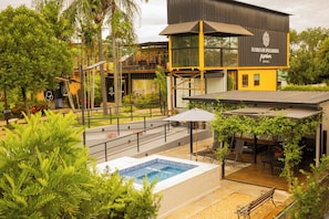 Um hotel moderno com piscina no terraço, área de estar ao ar livre e vegetação exuberante.