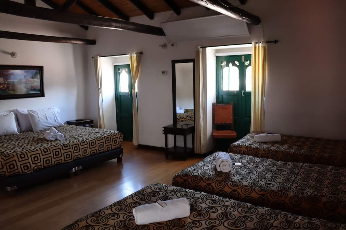 Quarto com duas camas, uma mesinha e um espelho.