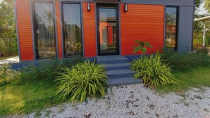 Uma casa moderna com fachada vermelha, janelas amplas e uma porta.