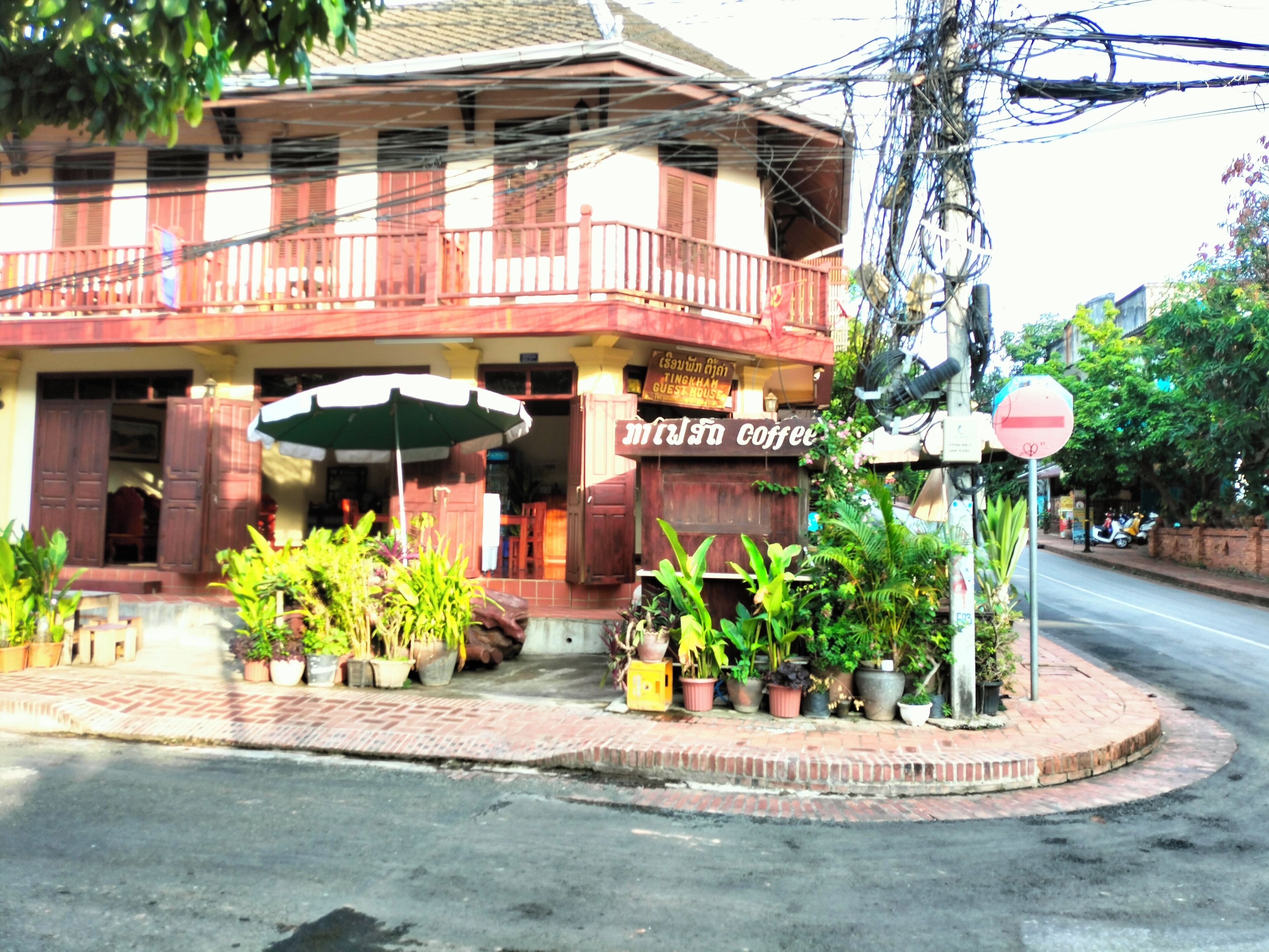 Um edifício com varanda, plantas em vasos e um letreiro que diz "Thai Coffee".