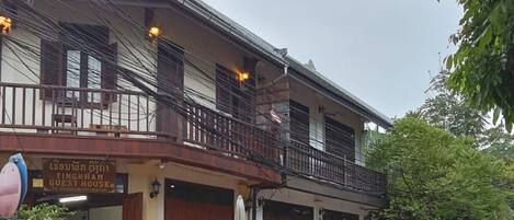 Um edifício com varanda e uma placa com a inscrição 'Tingkham Guest House'.