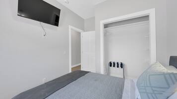 Quarto com cama, televisão na parede e guarda-roupa.