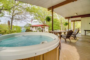 Uma banheira de hidromassagem em um deck de madeira com vista para uma casa e árvores.