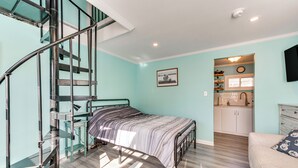 Quarto com cama, escada, cozinha compacta e sala de estar com sofá.