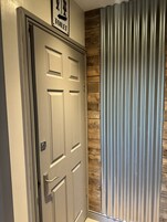 Uma porta com placa indicando um sanitário, parede de painel de madeira e cortina de metal.