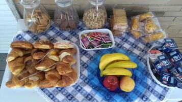Uma mesa com doces, frutas e lanches embalados.