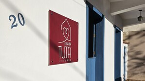 Um corredor com uma placa indicando o quarto 20, uma placa vermelha com o logo de coração e casa, e portas azuis.
