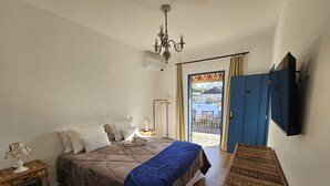 Quarto com cama, mesa de cabeceira, abajur e vista para o exterior.