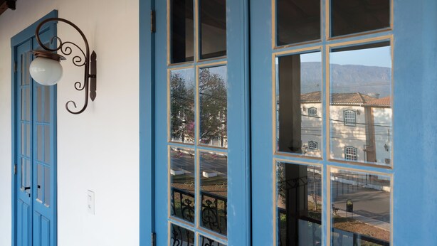 Uma porta azul com uma parede branca e uma janela com vários painéis.
