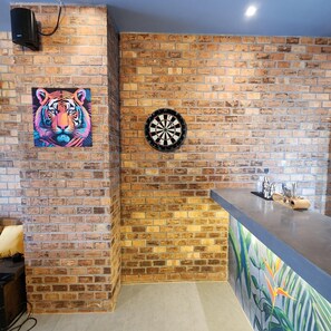 Quarto com parede de tijolos, um alvo de dardos e uma pintura colorida de tigre.