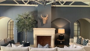 Uma sala de estar moderna com lareira, um candelabro, uma planta em vaso e um sofá com almofadas.