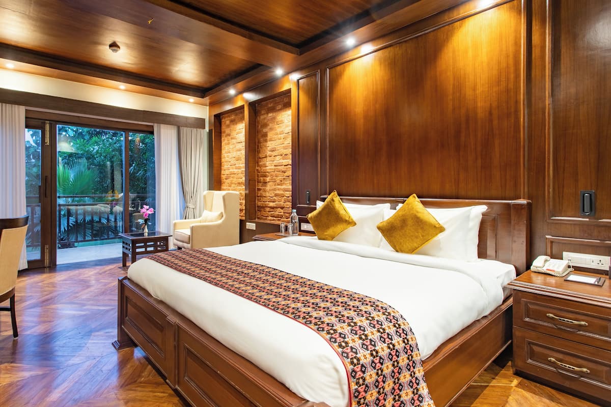 Um quarto espaçoso com uma cama grande, cabeceira de madeira e vista pela porta de vidro.