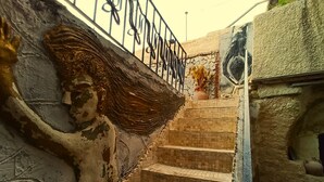 Escadaria com parede de textura rústica e corrimão de metal.