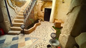 Um pátio com piso de azulejos, escadas com guarda-corpos de metal e uma porta.