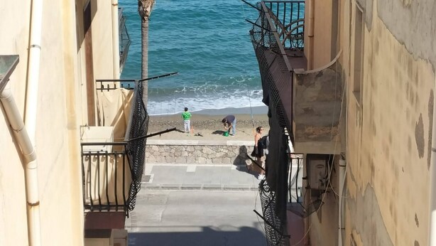 Uma rua estreita com varandas dando para uma praia.