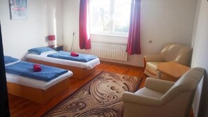 Quarto com duas camas, um sofá e uma poltrona.